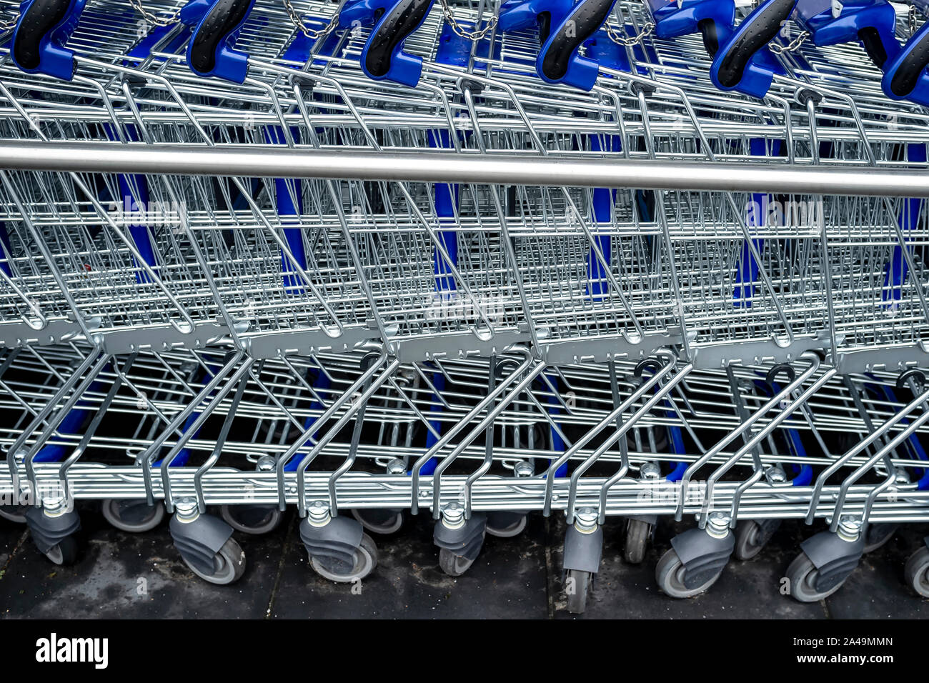 close-up side view of a stacked blue metal supermarket trolleys with ...