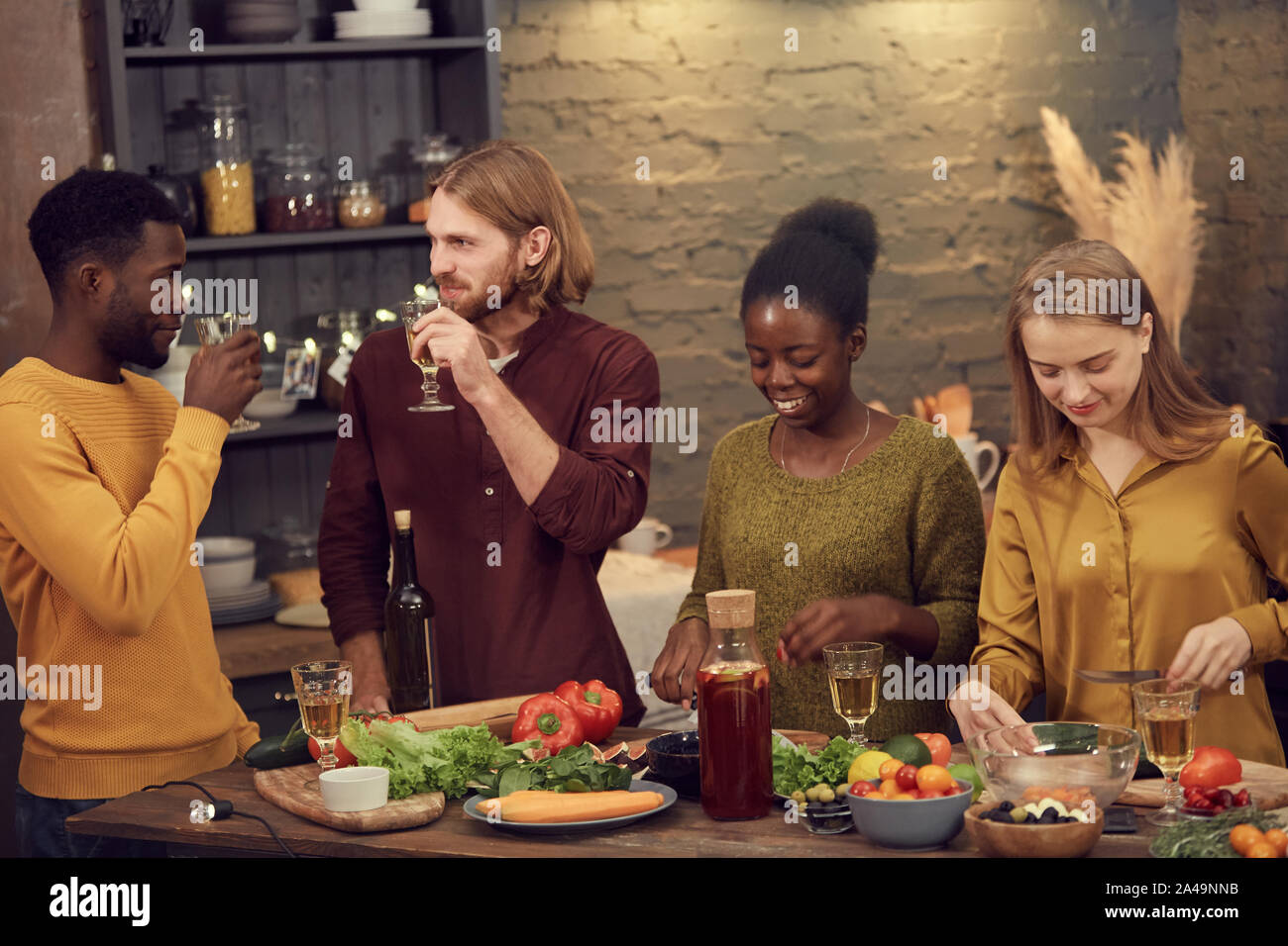 Multi-ethnic group of young people cooking dinner together standing at ...