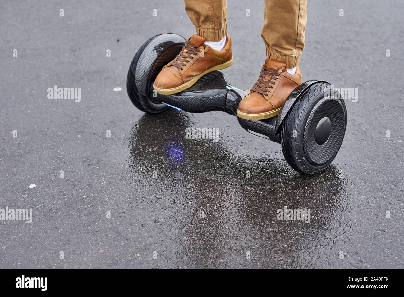 Man using hoverboard on asphalt road, close up. Feet on electrical ...