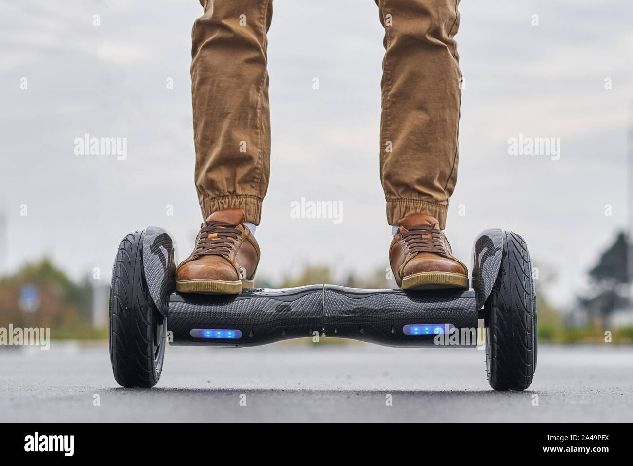 Man using hoverboard on asphalt road, close up. Feet on electrical ...