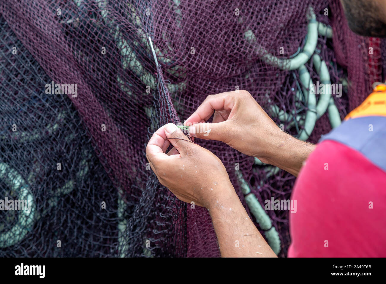 Fisherman repairing fishing nets. Fisherman with net in hands mending ...