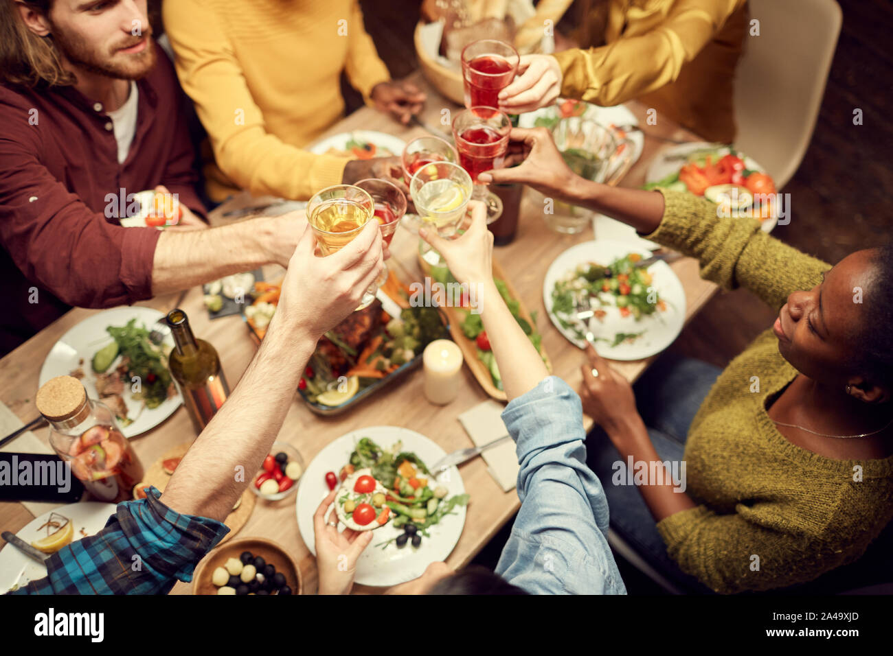 Above view of people raising glasses over dinner table while enjoying ...