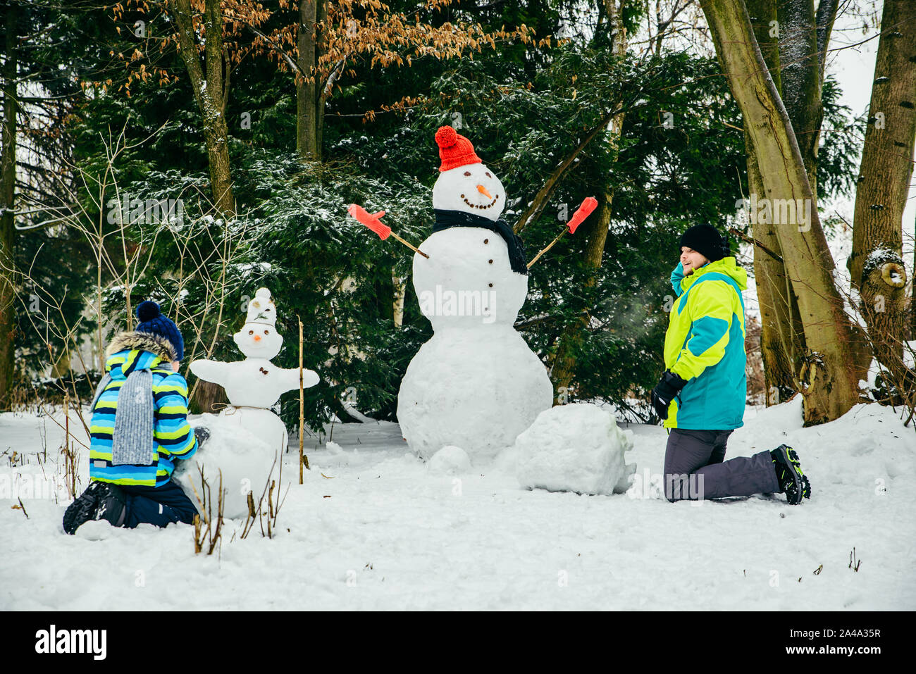 little cute boy making snowman. rolling big snowball Stock Photo - Alamy