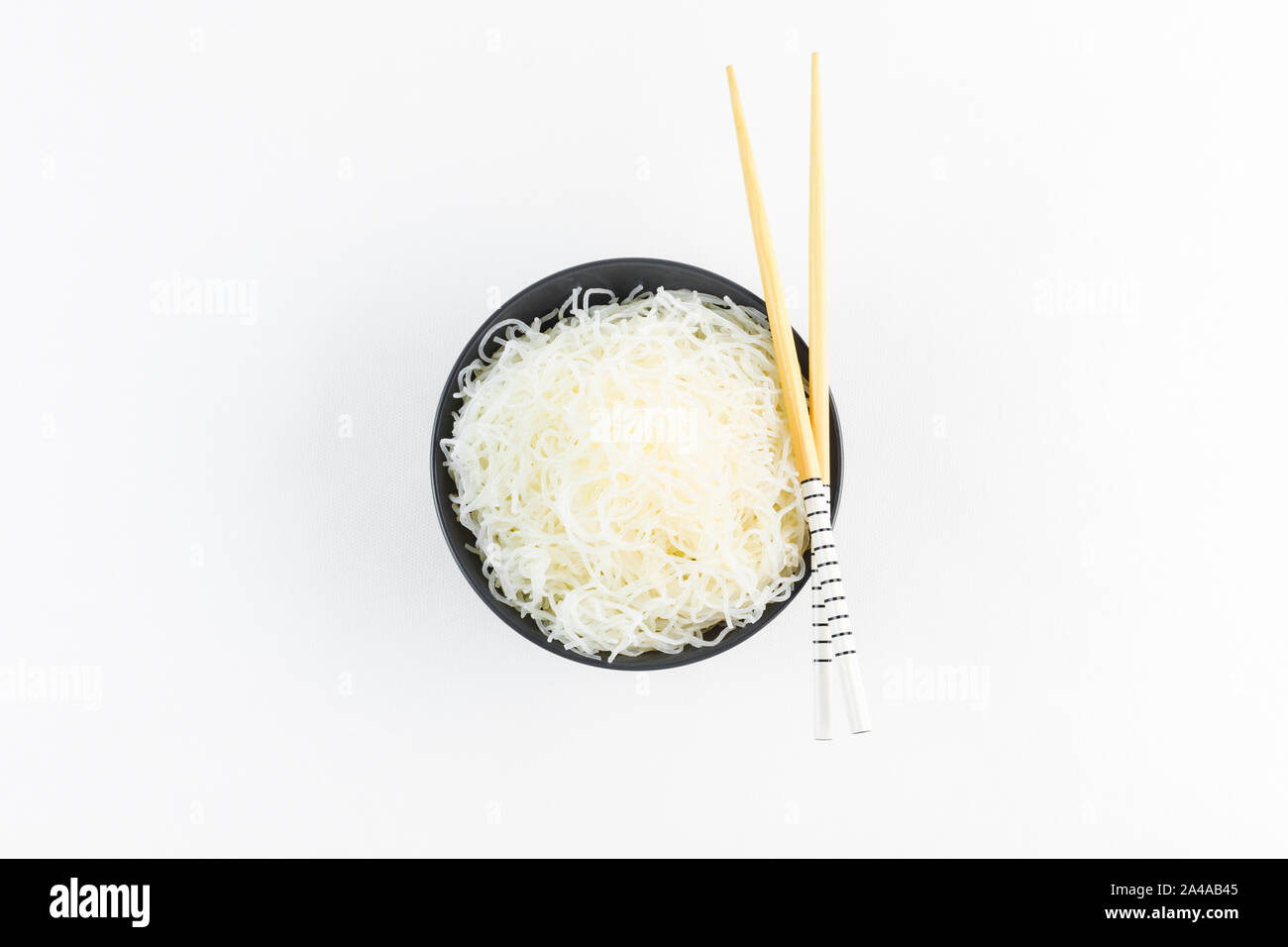 Cellophane rice noodles in a black bowl with chopsticks on white ...