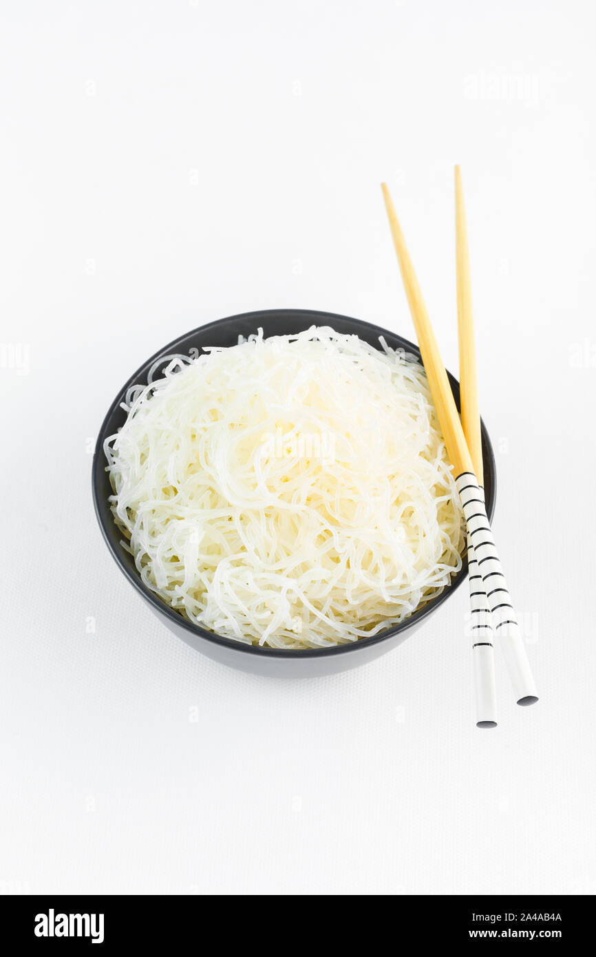 Cellophane rice noodles in a black bowl with chopsticks on white ...