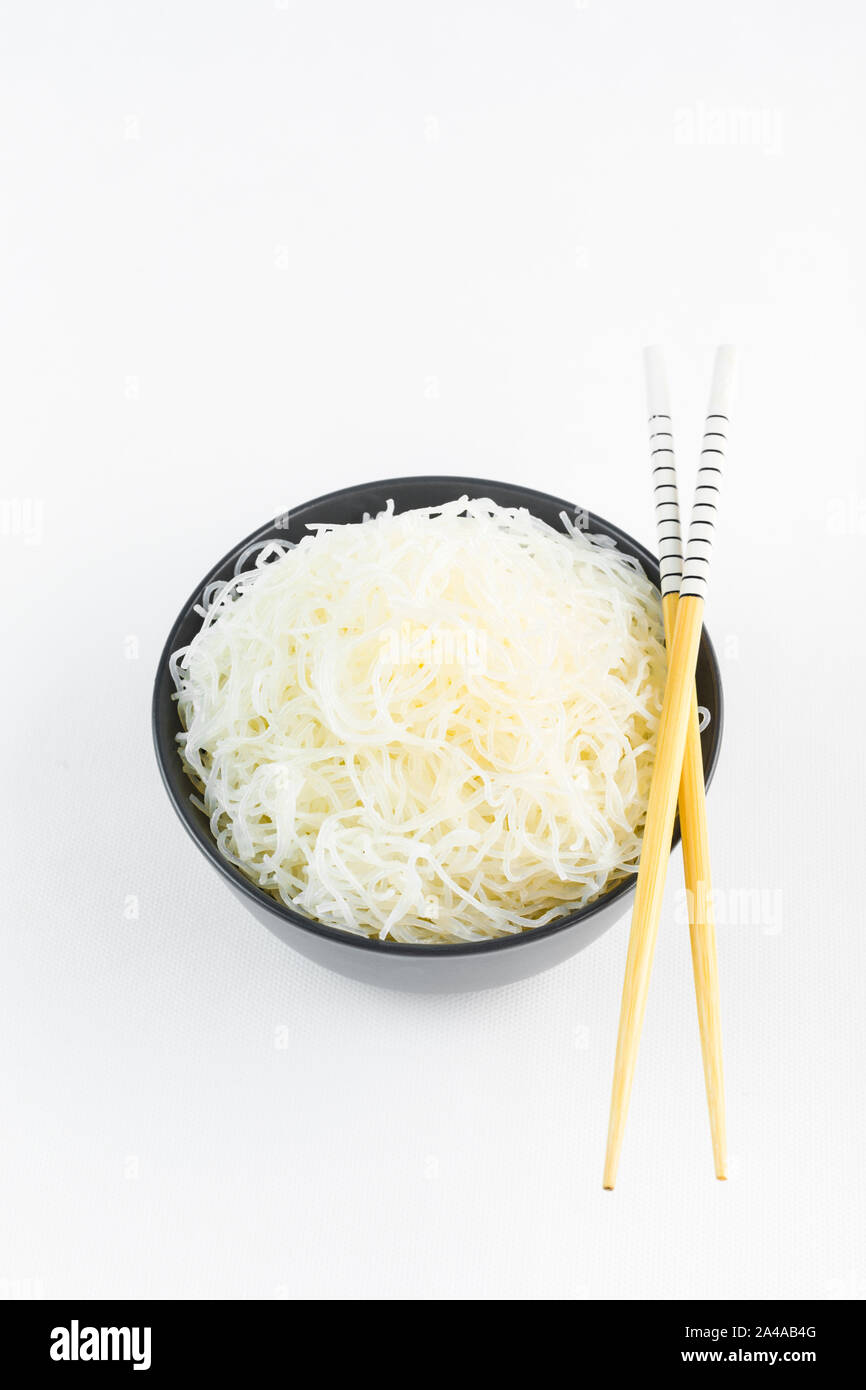 Cellophane rice noodles in a black bowl with chopsticks on white ...