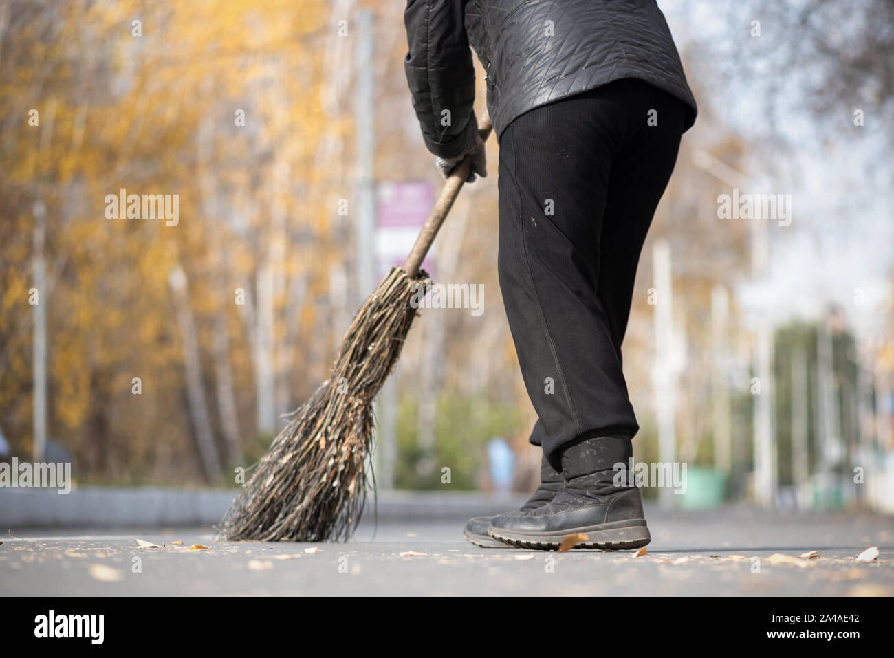Cleaner sweeping the asphalt road by broom outdoors Stock Photo - Alamy