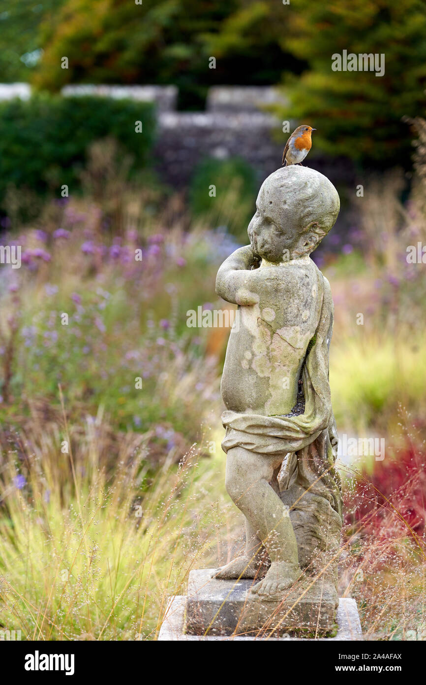 A robin perched on the head of a statue in the grounds of St Fagans ...