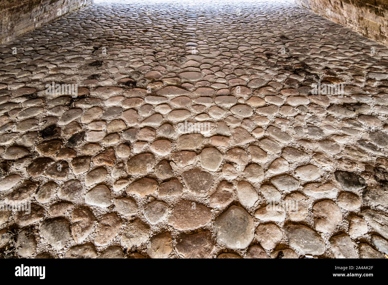 Old cobblestone pavement in natural daylight passes through the arch ...