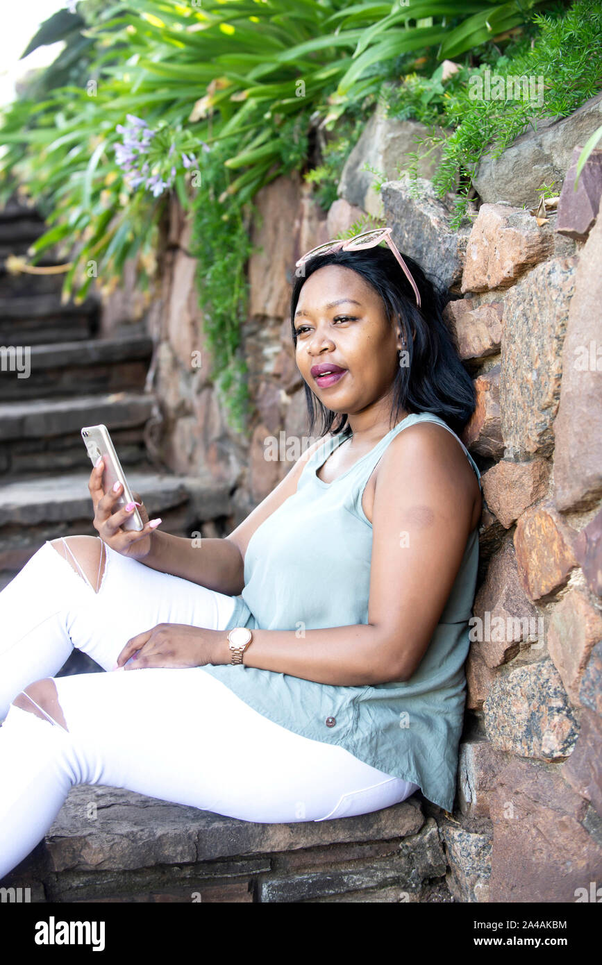 Young woman sitting on steps using her mobile phone Stock Photo - Alamy