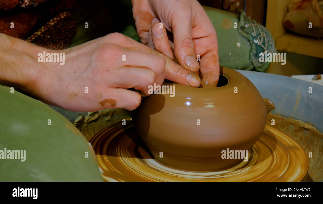 Professional potter shaping bowl with special tool in pottery workshop ...