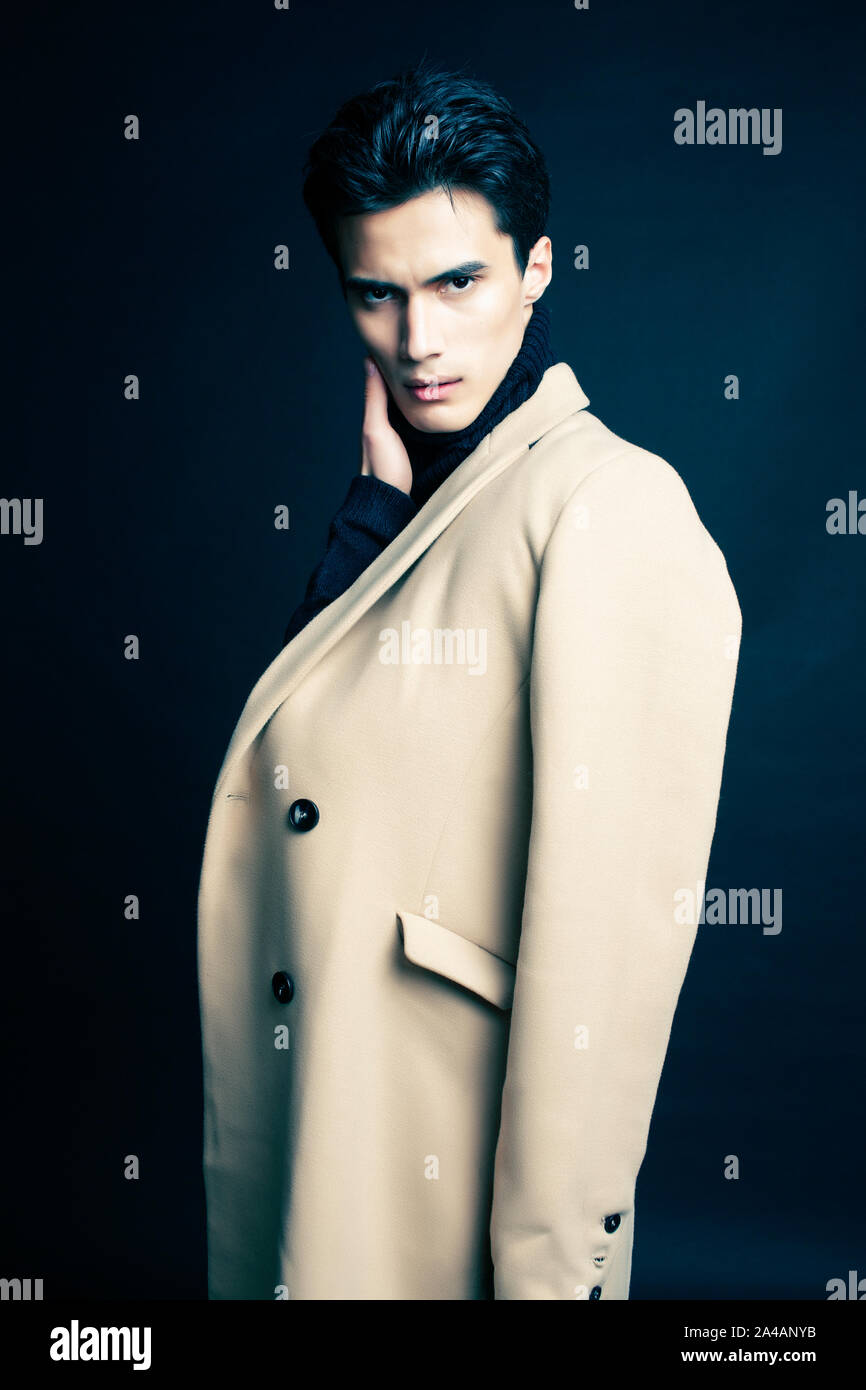 cool real young man in coat on black background posing, lifestyle ...