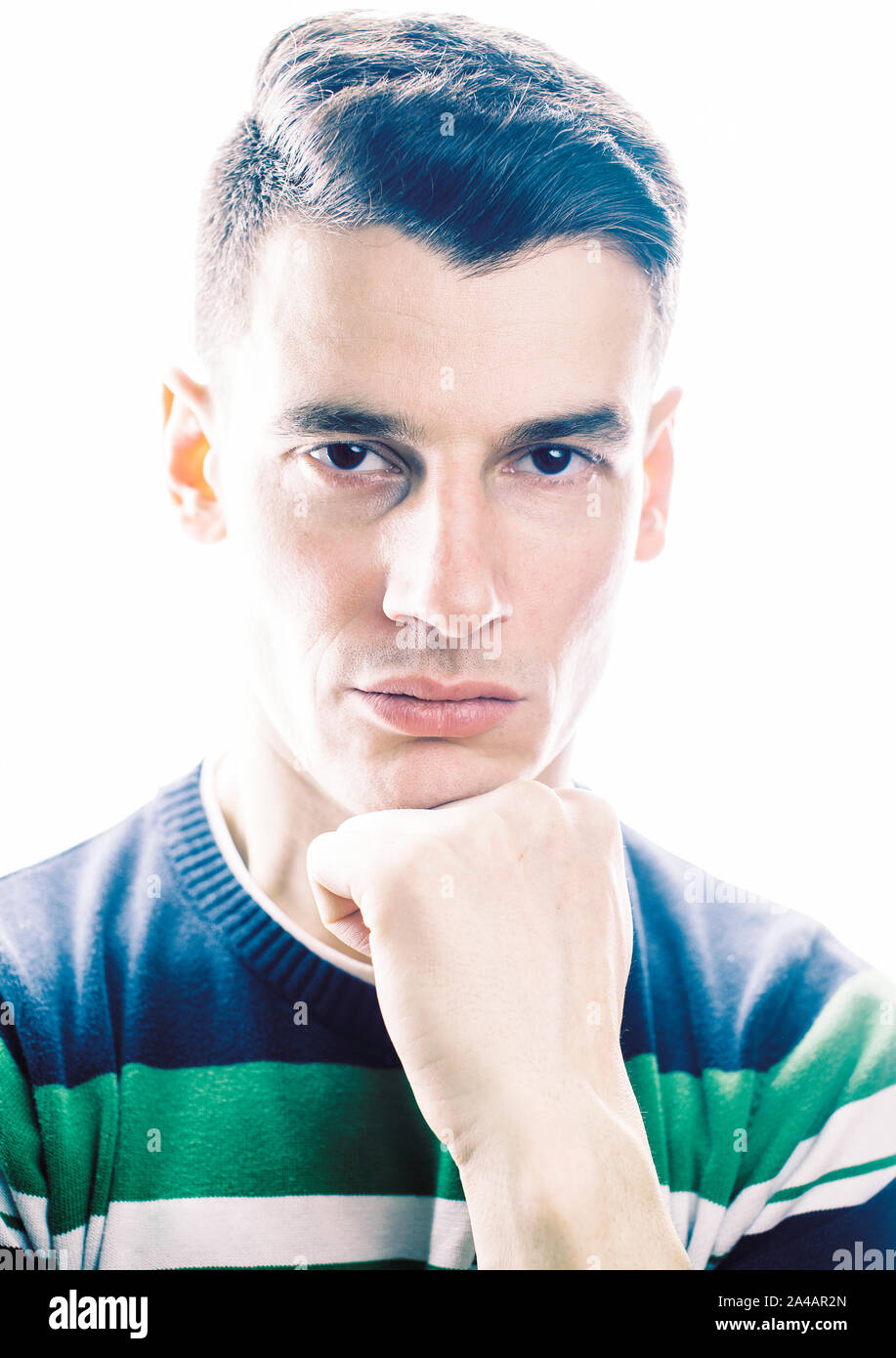 Portrait of a smart serious young man standing against white background ...