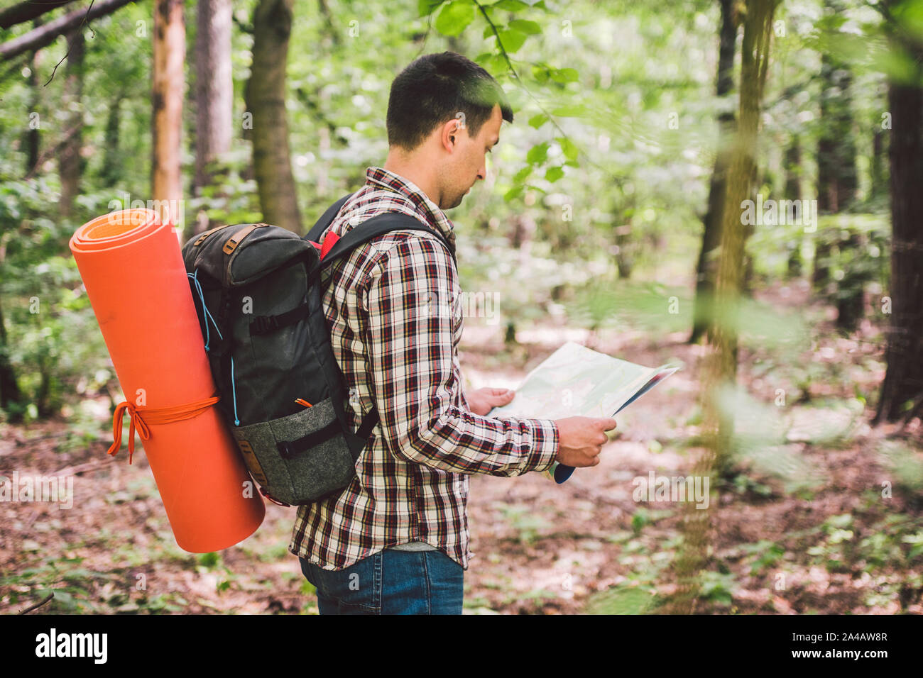 Man with Backpack and map searching directions in wilderness area ...