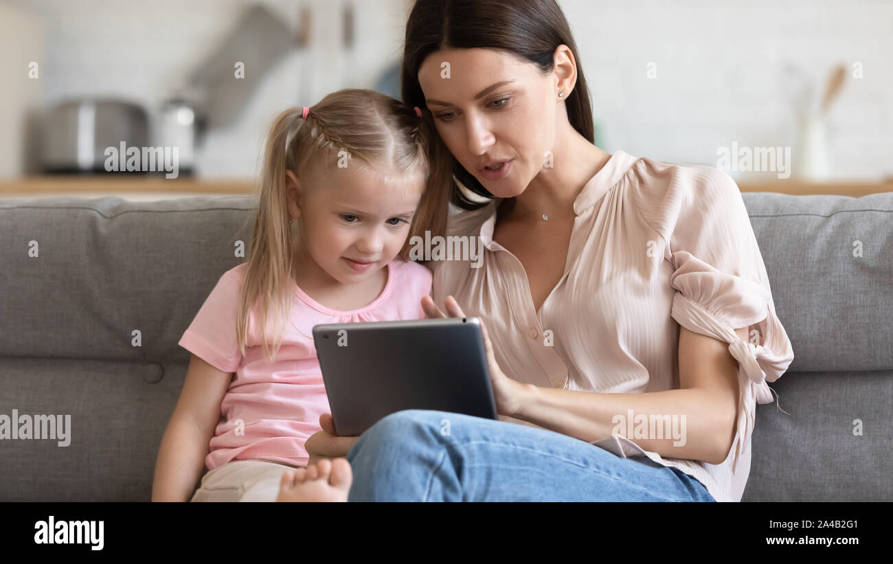 Mother teaching little daughter to use computer tablet close up Stock ...