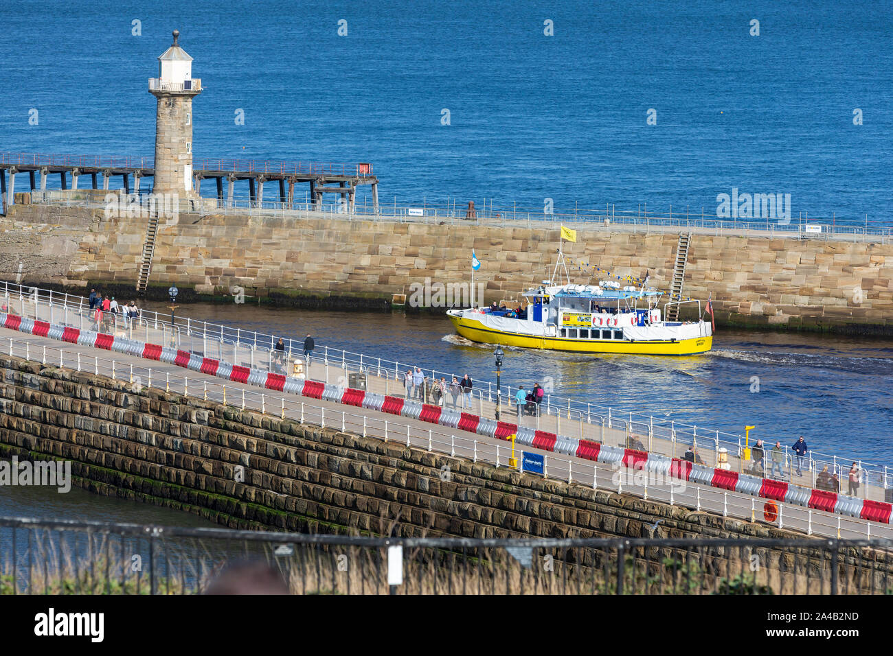 A pleasure cruiser leaves Whitby Harbour viewed from the high promenade ...