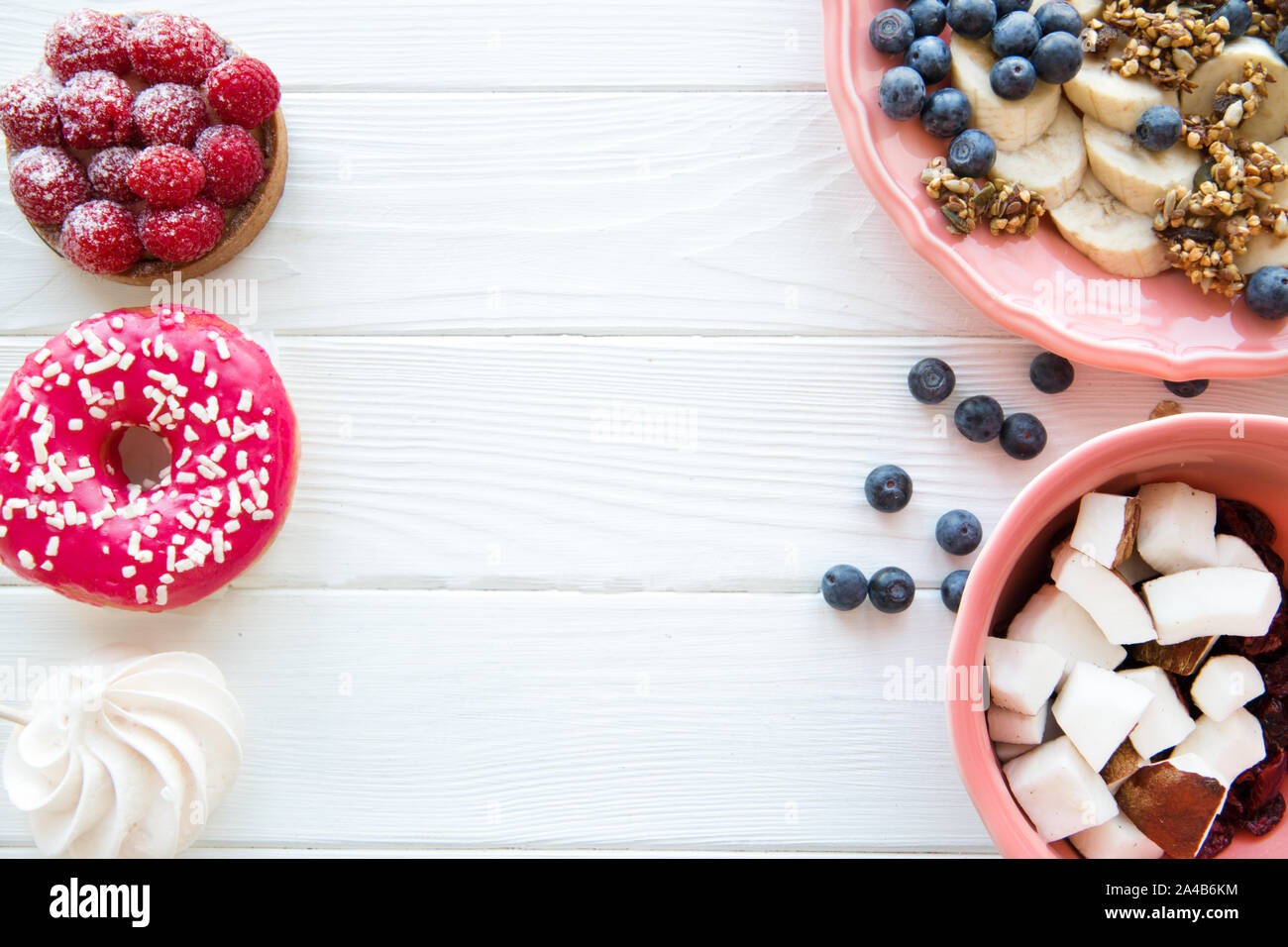 Sweet unhealthy desserts and healthy tasty snacks on white wooden table ...