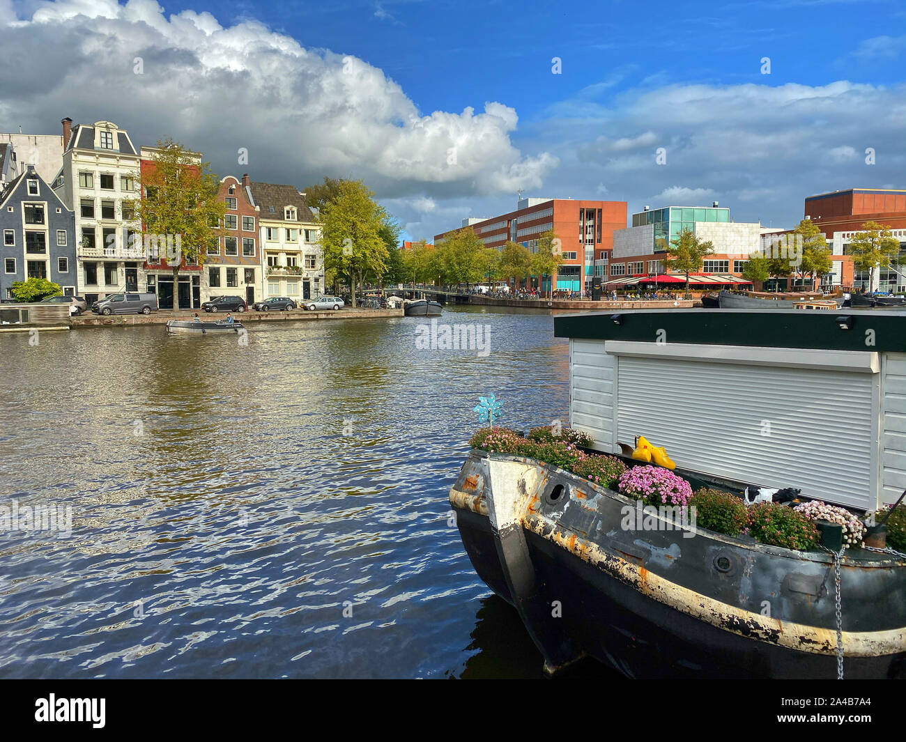 Amsterdam canal with typical dutch houses and houseboats, boats in the evening with beautiful ...