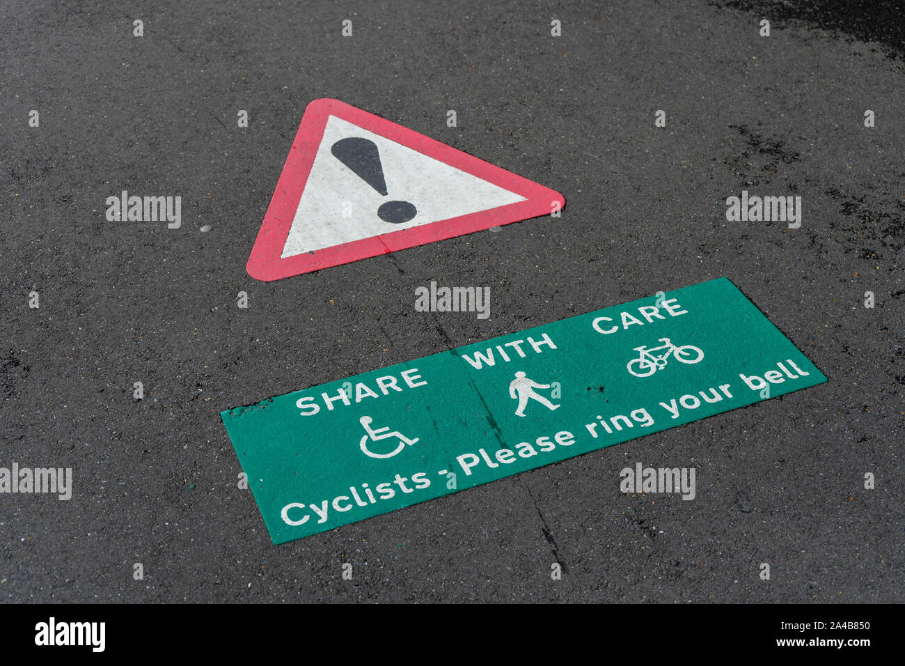 A painted sign on a pavement asking cyclists to beware of pedestrians ...