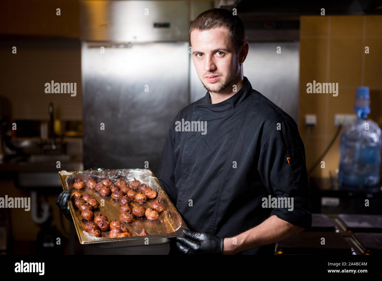 Portrait male chef with cooked food standing in kitchen. Theme cooking ...