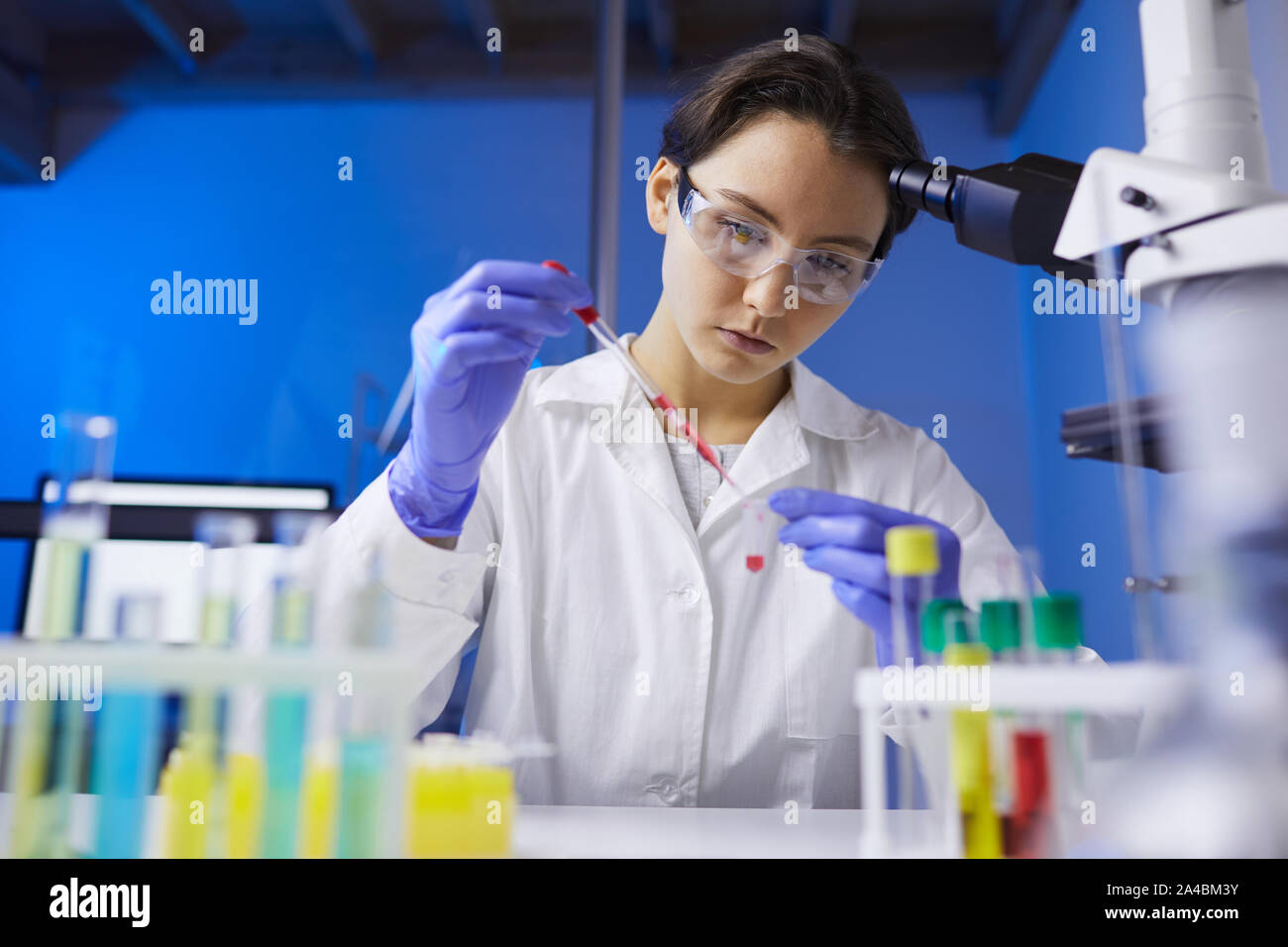 Low angle portrait of young female scientist preparing blood sample ...