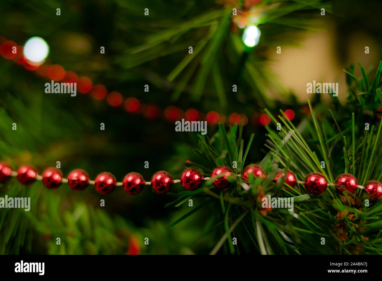 Chain of red Christmas balls placed on a Christmas tree with blurred ...