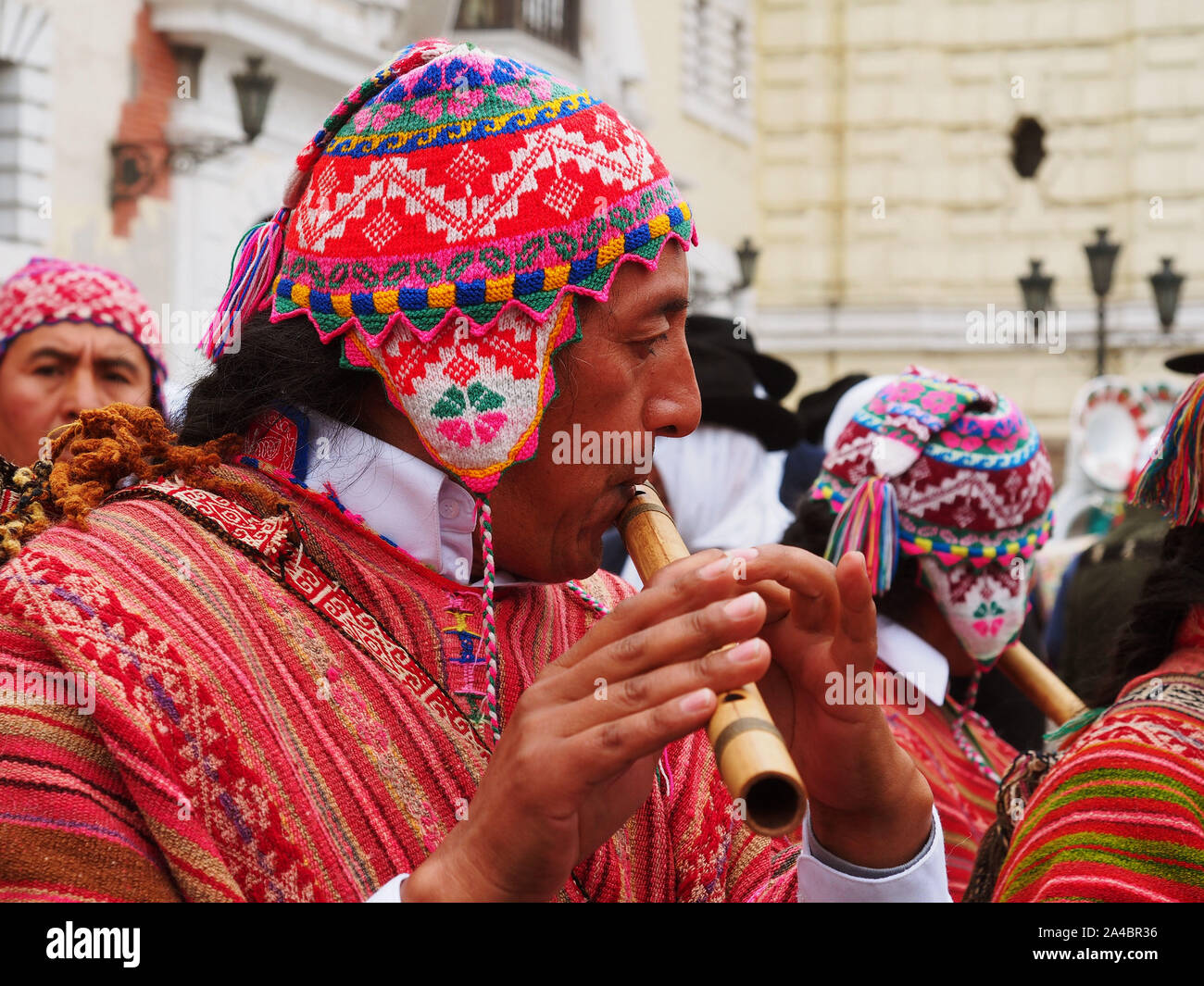 An indigenous musician playing a flute and wearing typical costume ...