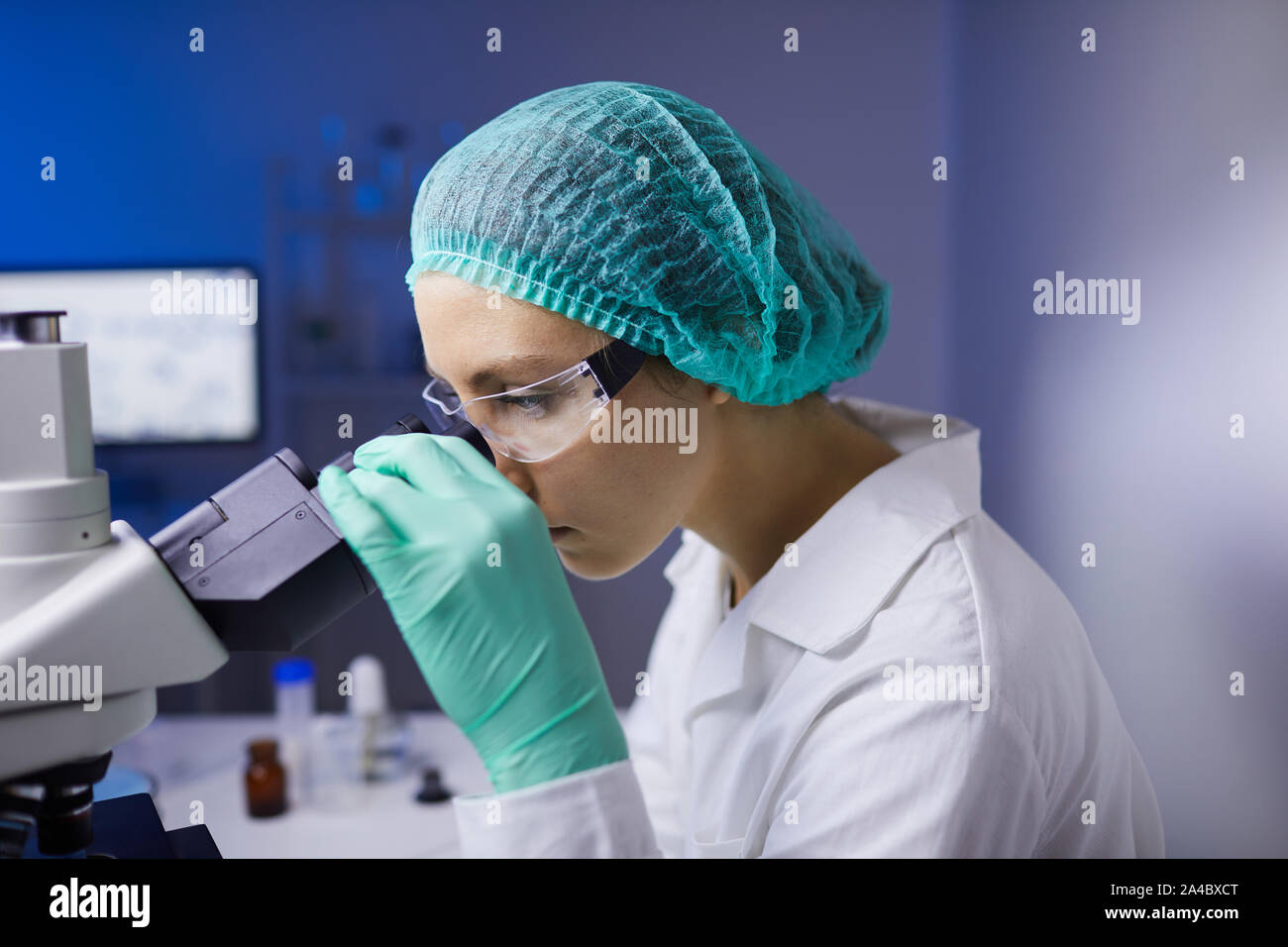 Side view portrait of young woman looking in microscope while working ...