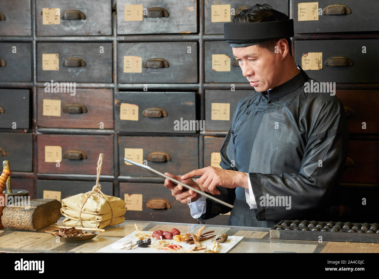 Traditional Chinese medicine practitioner following recipe on tablet ...
