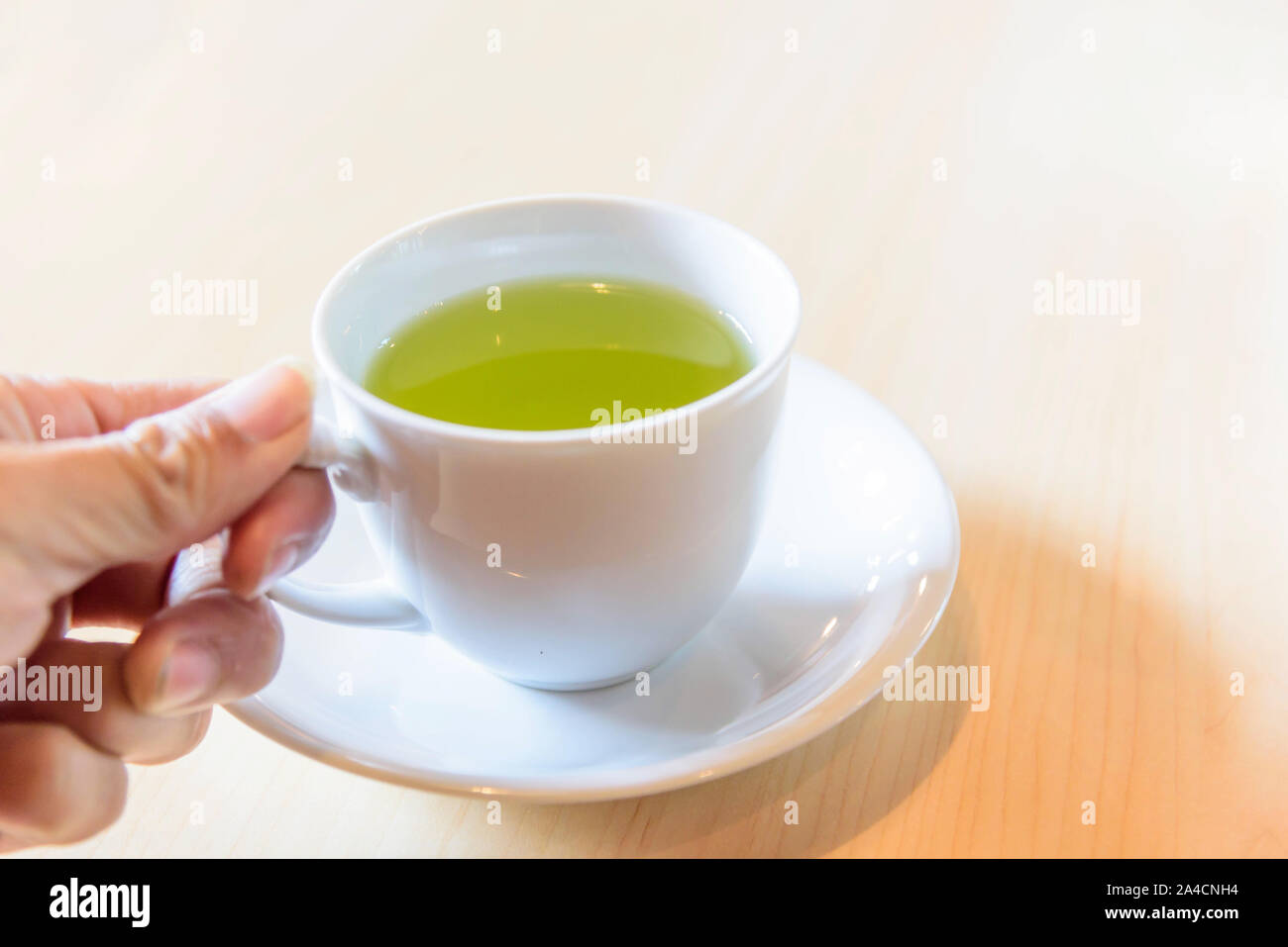 The man hold the hot green tea on his hand before drink / hot matcha ...