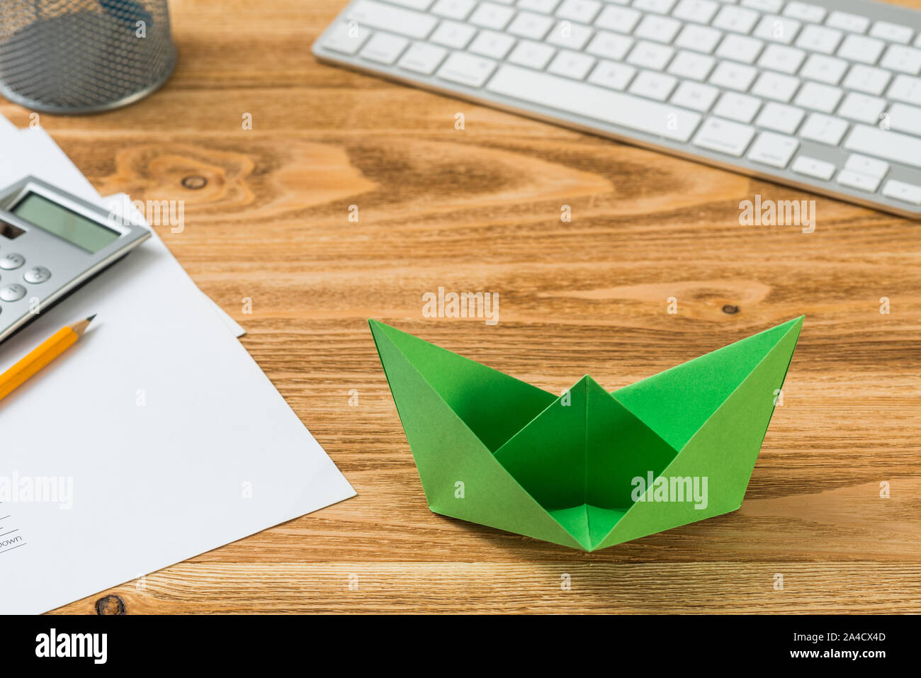 Modern office workspace with green paper ship Stock Photo - Alamy