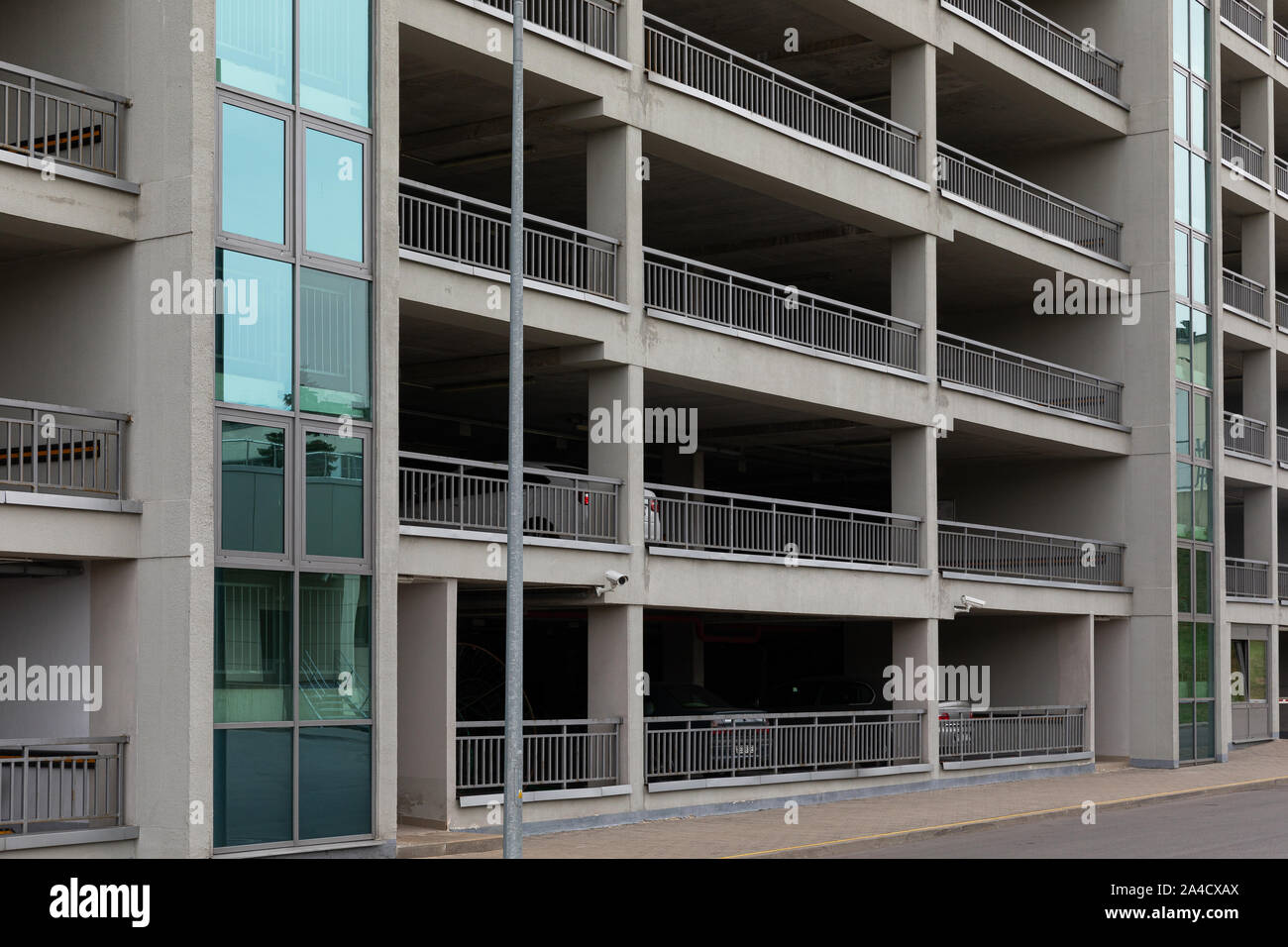 Car parking building facade with gray concrete walls and glass windows ...