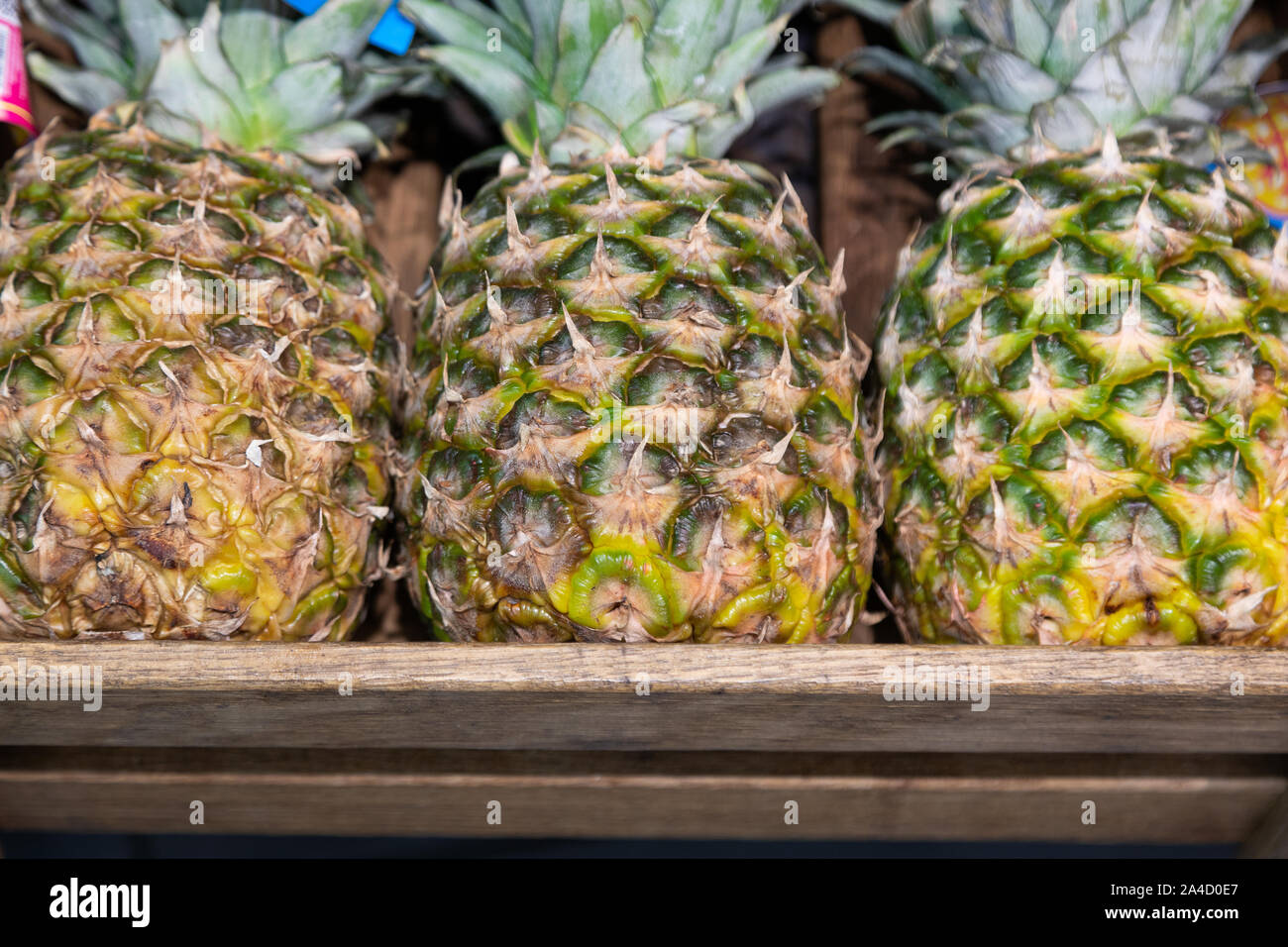 Wooden lug box with exotic pineapple on supermarket counter Stock Photo ...