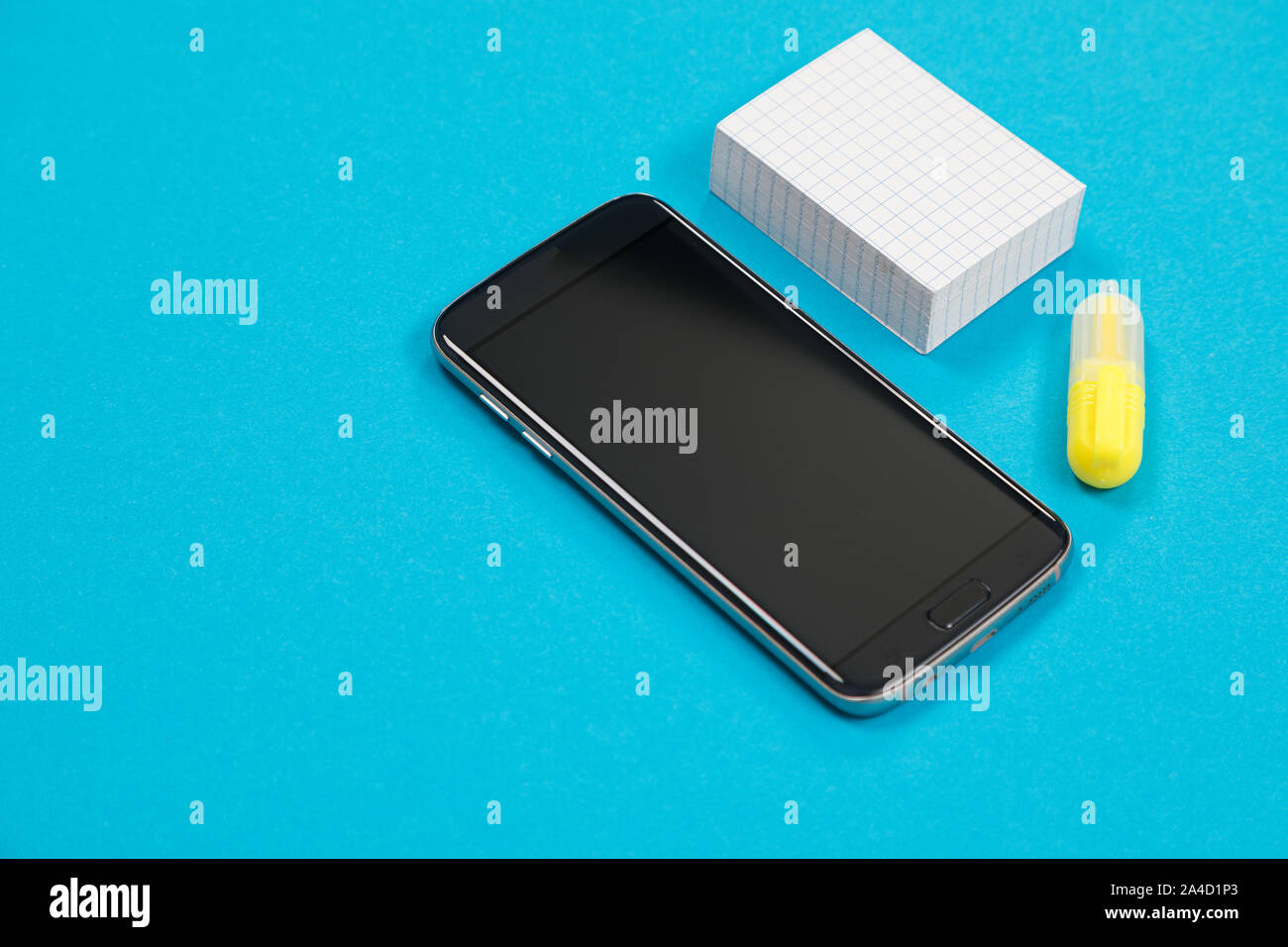 Black smartphone, a pile of scratch paper and one yellow textliner on ...