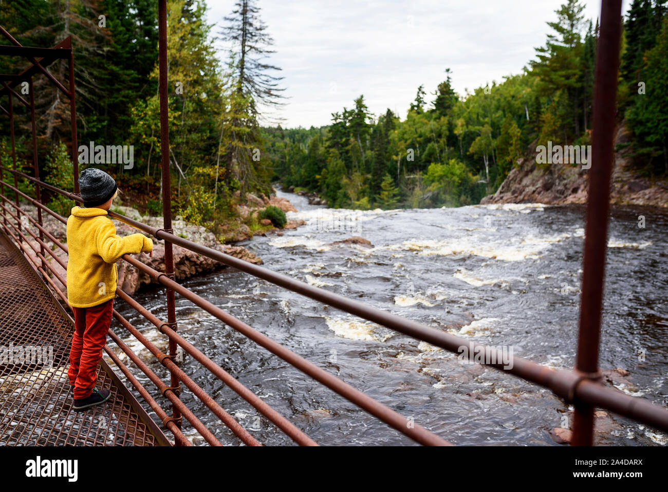 Boy standing on a bridge looking at river, Untied States Stock Photo ...
