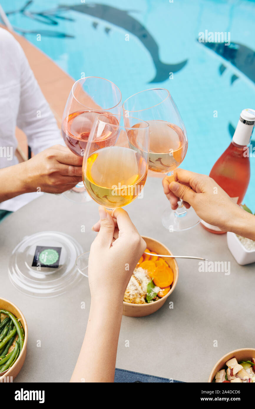 People sitting at cafe table outdoors, eating lunch and toasting with ...