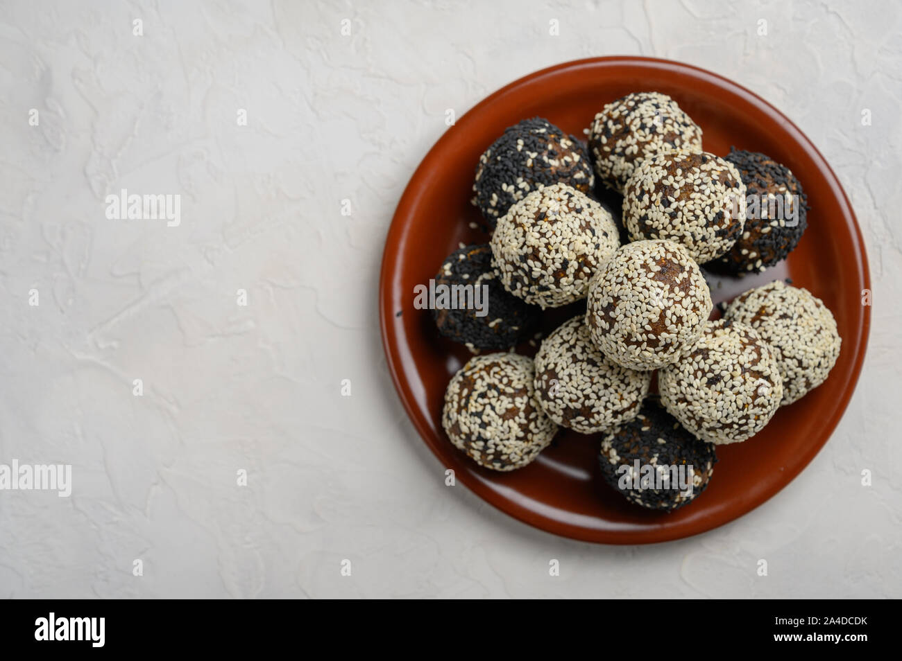 Homemade energy balls on a brown ceramic plate on a white background ...