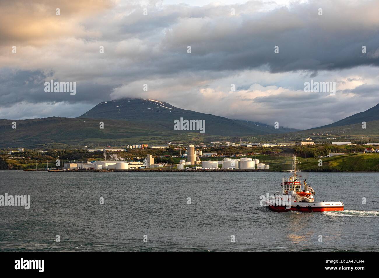 PILOT BOAT IN FRONT OF THE COMMERCIAL PORT WITH THE FUEL STORAGE TANKS ...
