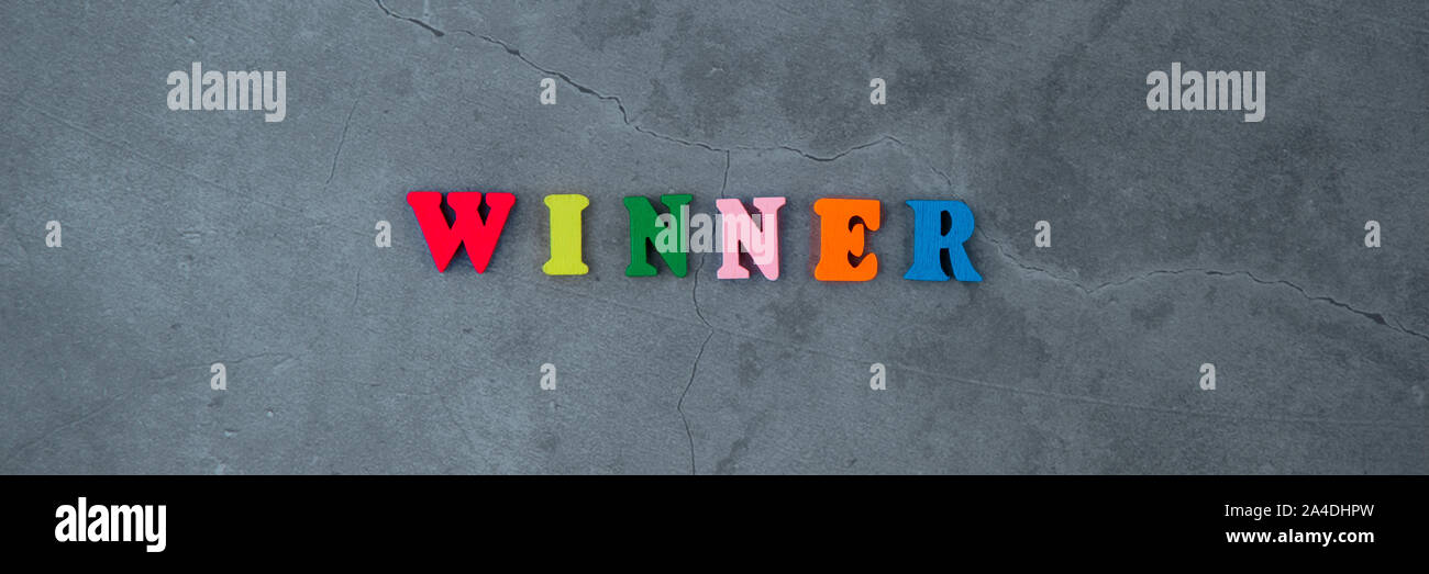 The multicolored winner word is made of wooden letters on a grey ...