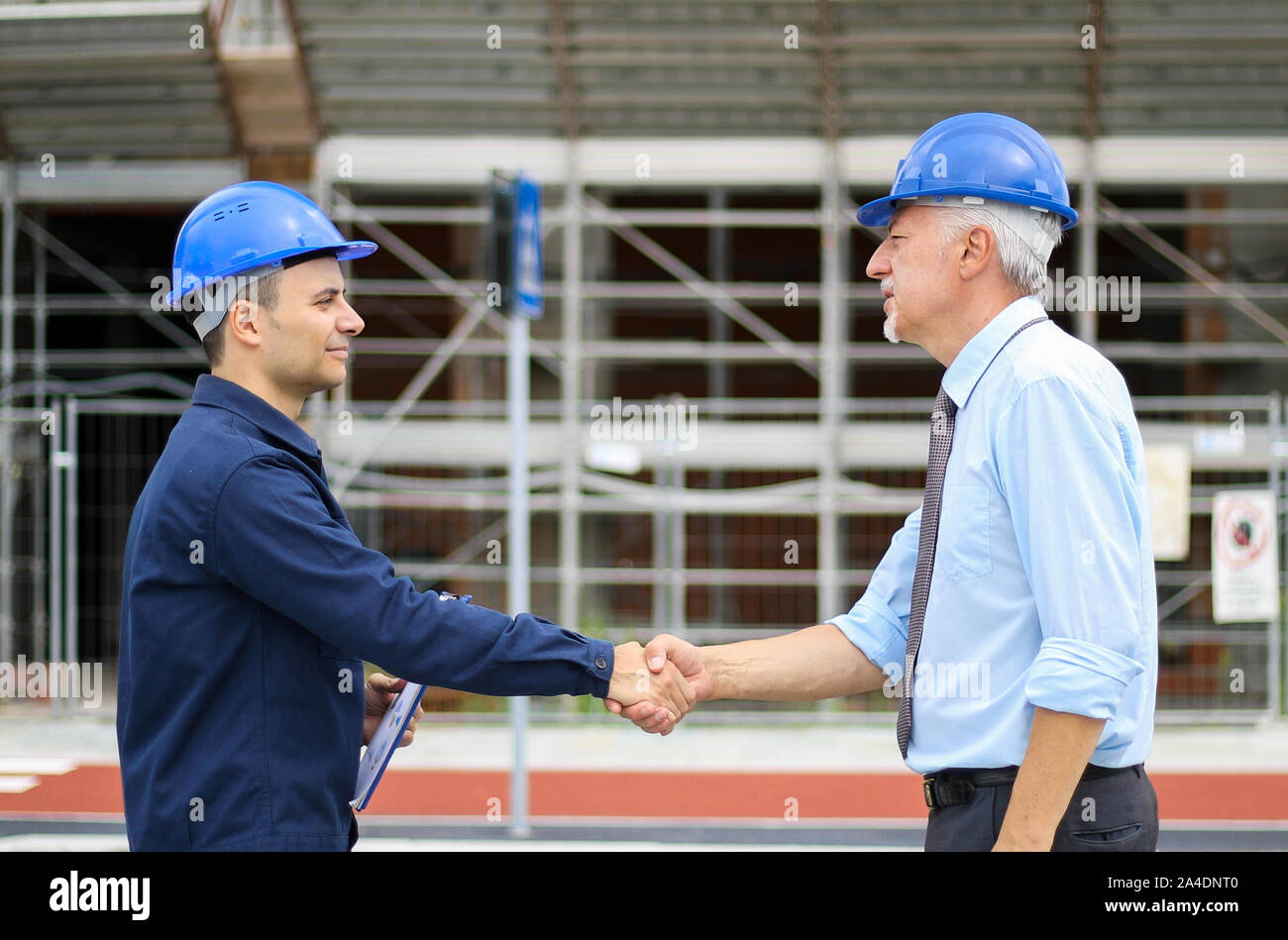 Two engineers shaking hands at a construction site Stock Photo - Alamy