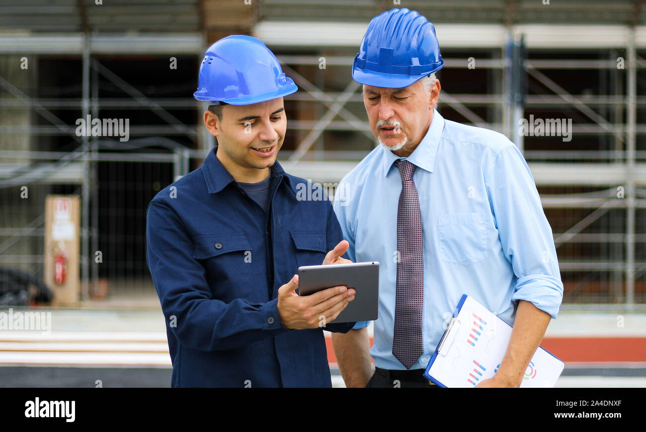 Two architect developers reviewing building plans at construction site ...