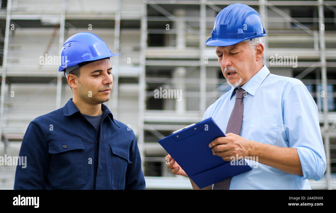 Two architect developers reviewing building plans at construction site ...