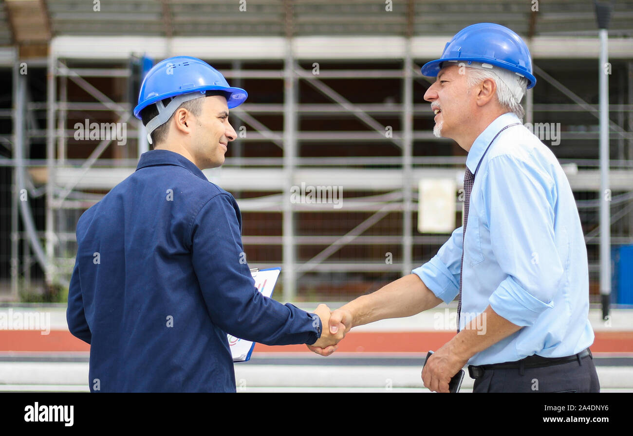 Two engineers shaking hands at a construction site Stock Photo - Alamy