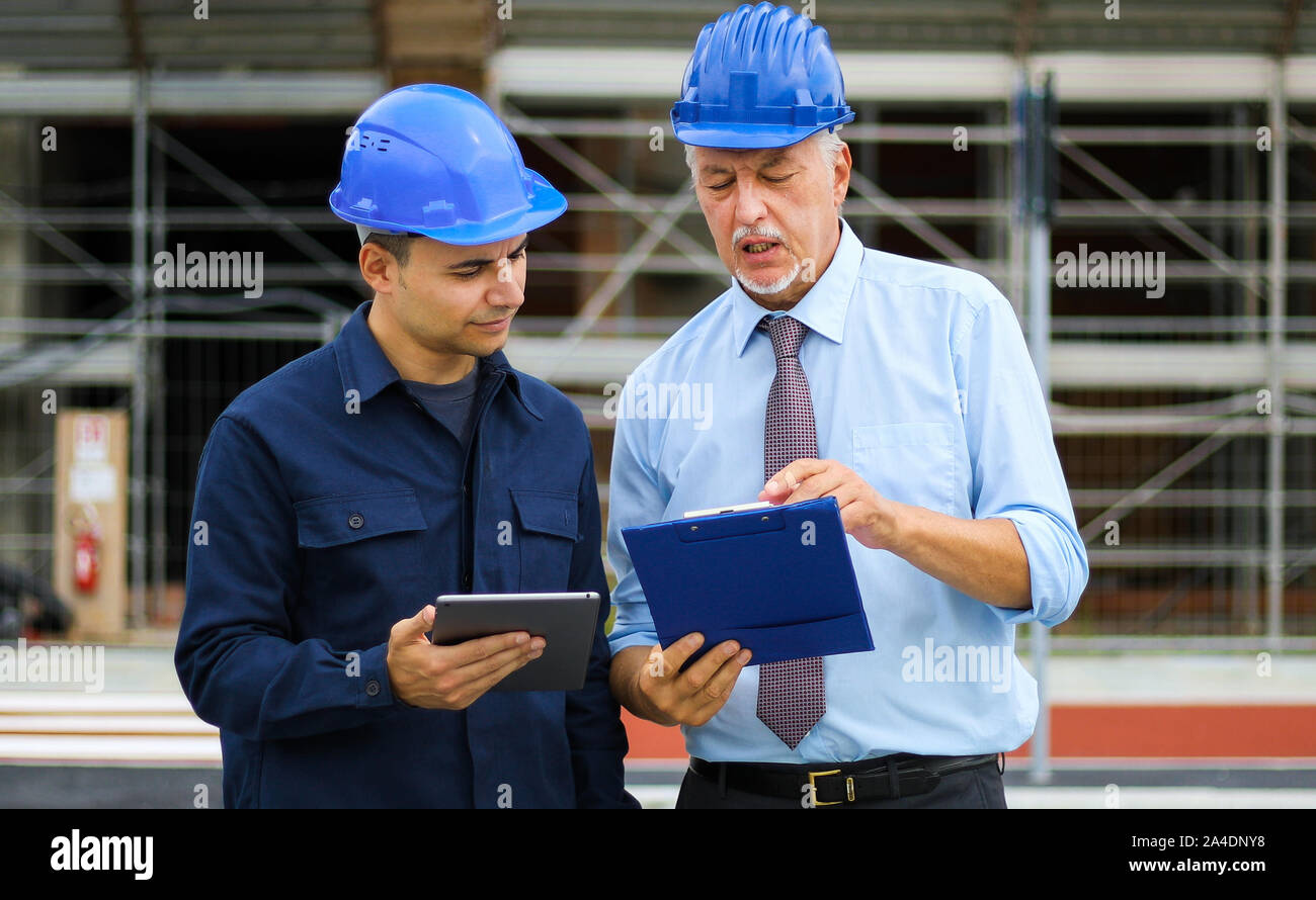 Two architect developers reviewing building plans at construction site ...