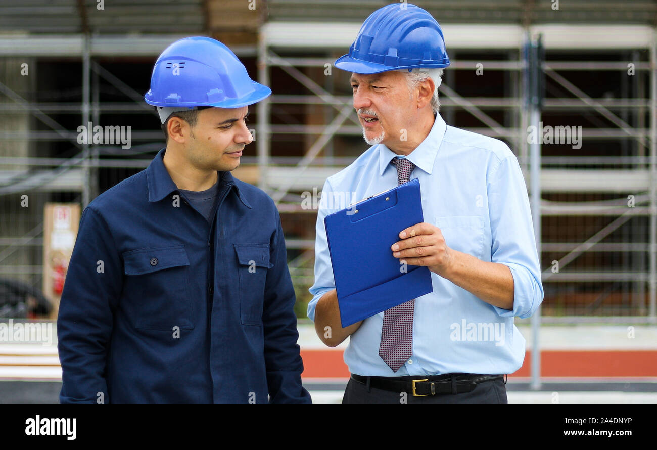 Two architect developers reviewing building plans at construction site ...