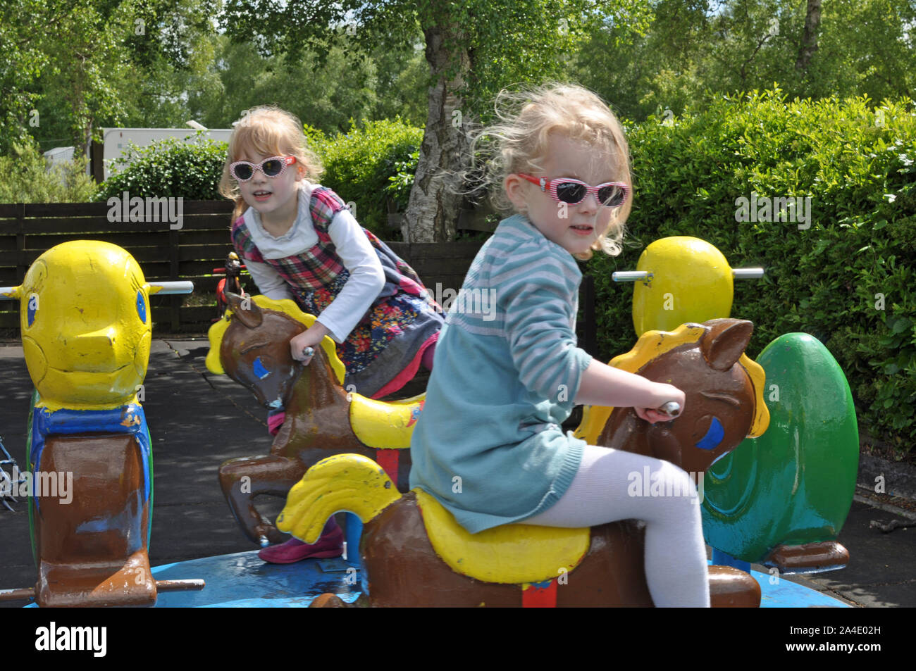 Two young girls on roundabout Stock Photo - Alamy