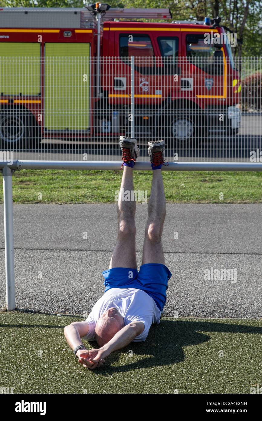 FIREFIGHTER DOING STRETCHING EXERCISES ON A BAR IN FRONT OF A FIRE ...
