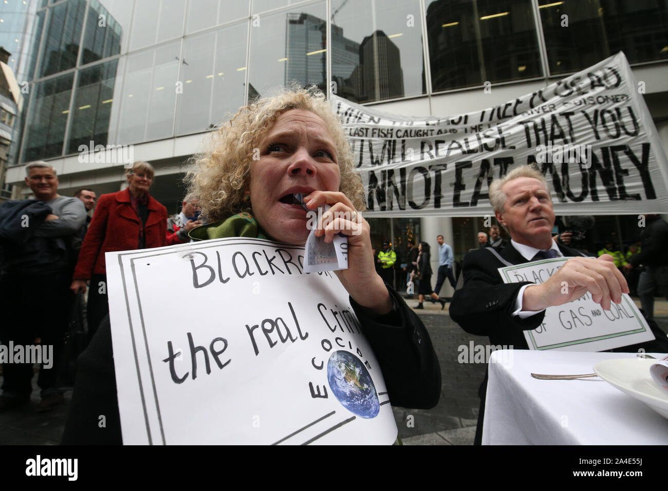 Protesters 'eat money' as a form of demonstration outside the BlackRock ...