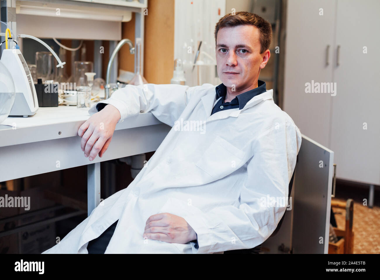 male chemist conducts experiments with liquids in chemical laboratory ...