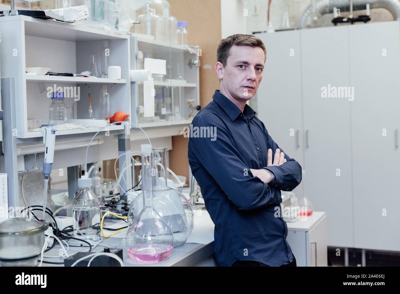 male chemist conducts experiments with liquids in chemical laboratory ...